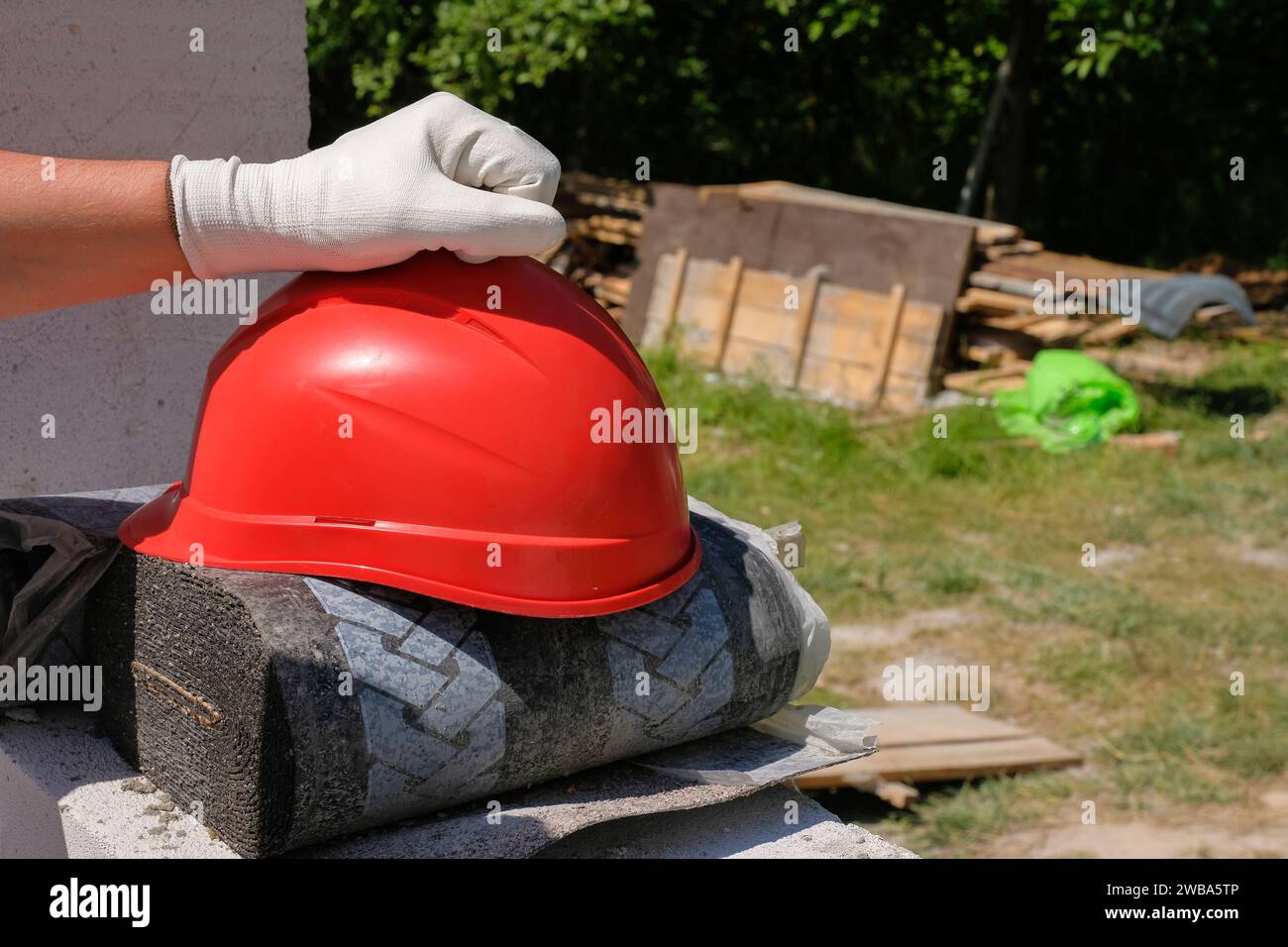 Part of a builders hand and a safety helmet at a construction site ...