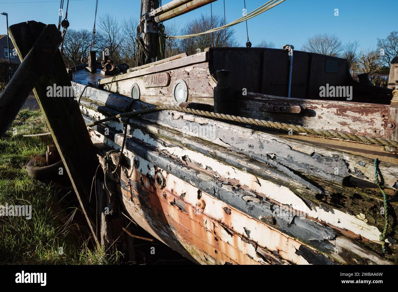 Close up of the side of a old wooden hulled boat flaking paint rust ...
