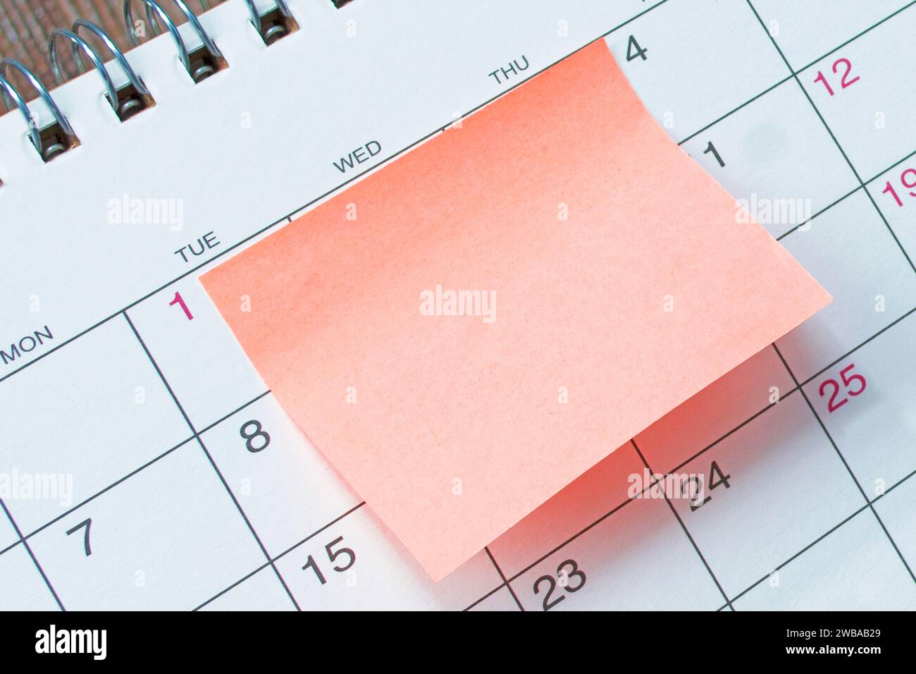 Orange paper sticky note and stuck to a calendar background. Reminder ...