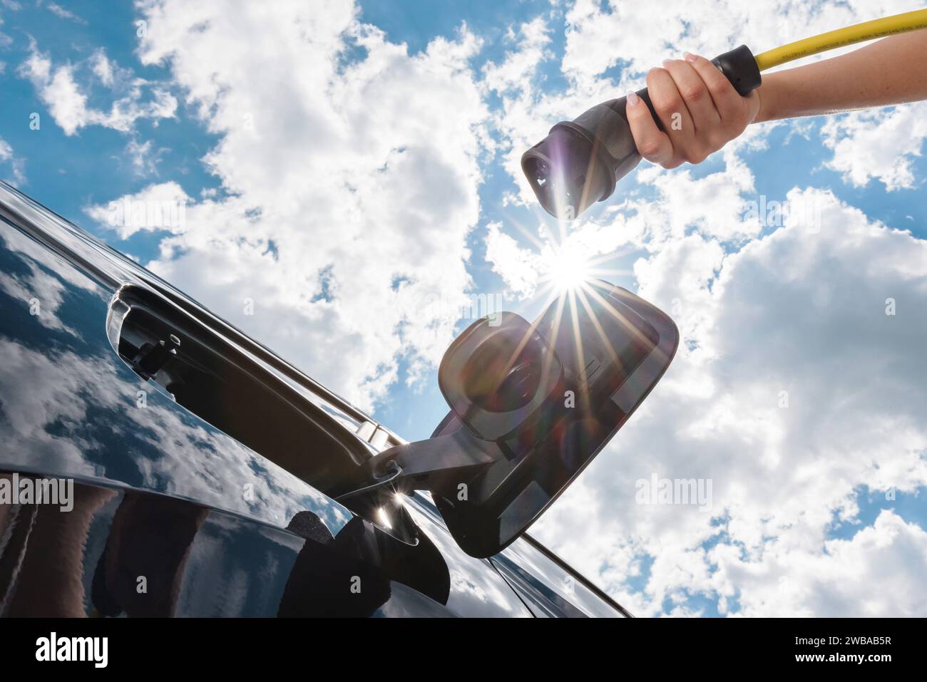 Female hand charging electric car with blue sky, photo from below Stock ...