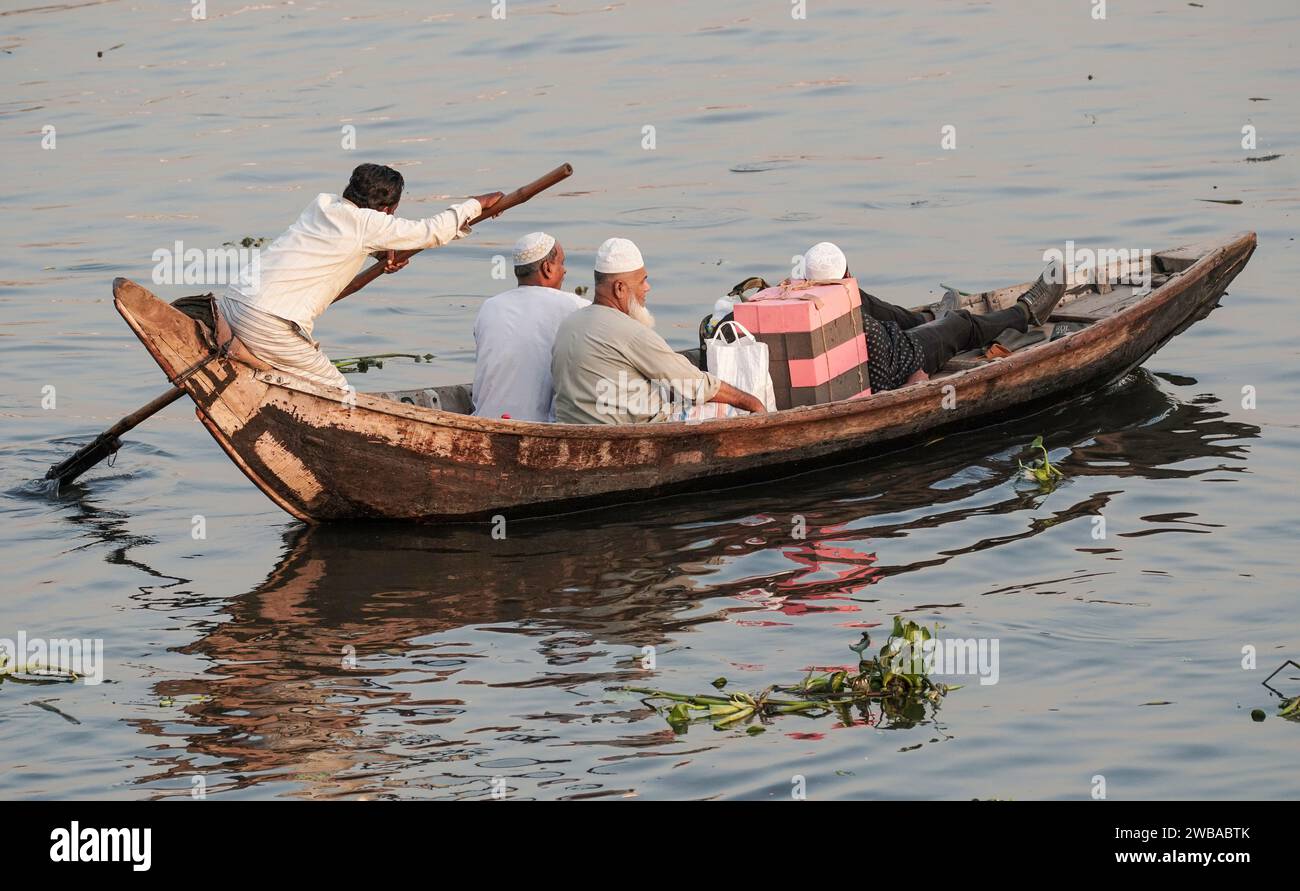 Passengers in an open wooden ferry boat cross the Buriganga River in Dhaka, Bangladesh Stock ...