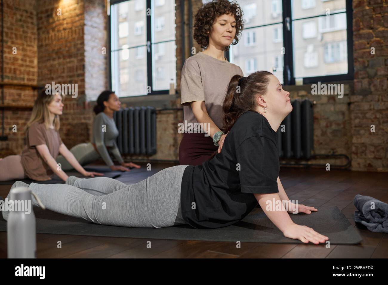 Side view of young female fitness instructor helping girl with ...