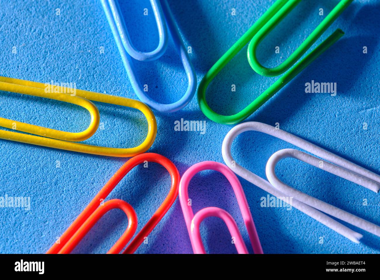 Multi colored paper clips are folded in shape star blue background ...