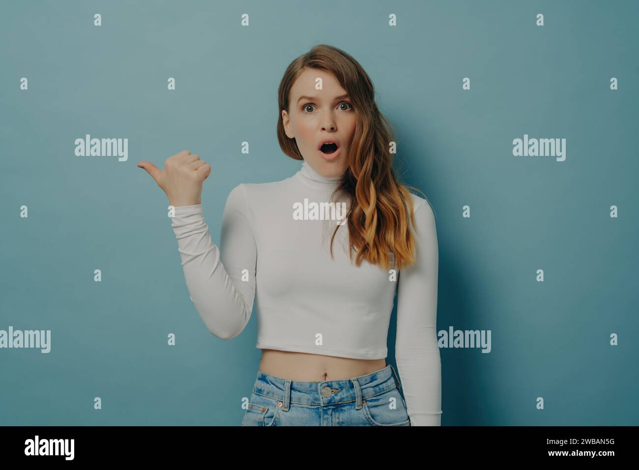 Shocked young woman with a hand gesture pointing sideways, expressing ...