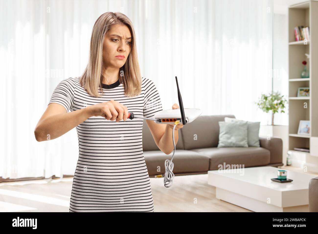 Angry young woman fixing a router in an apartment Stock Photo - Alamy