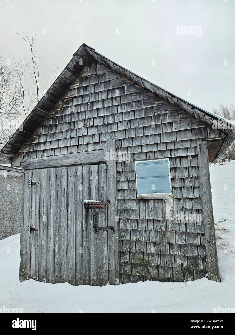 An aged, wooden cabin is situated on a snowy incline, basking in the ...