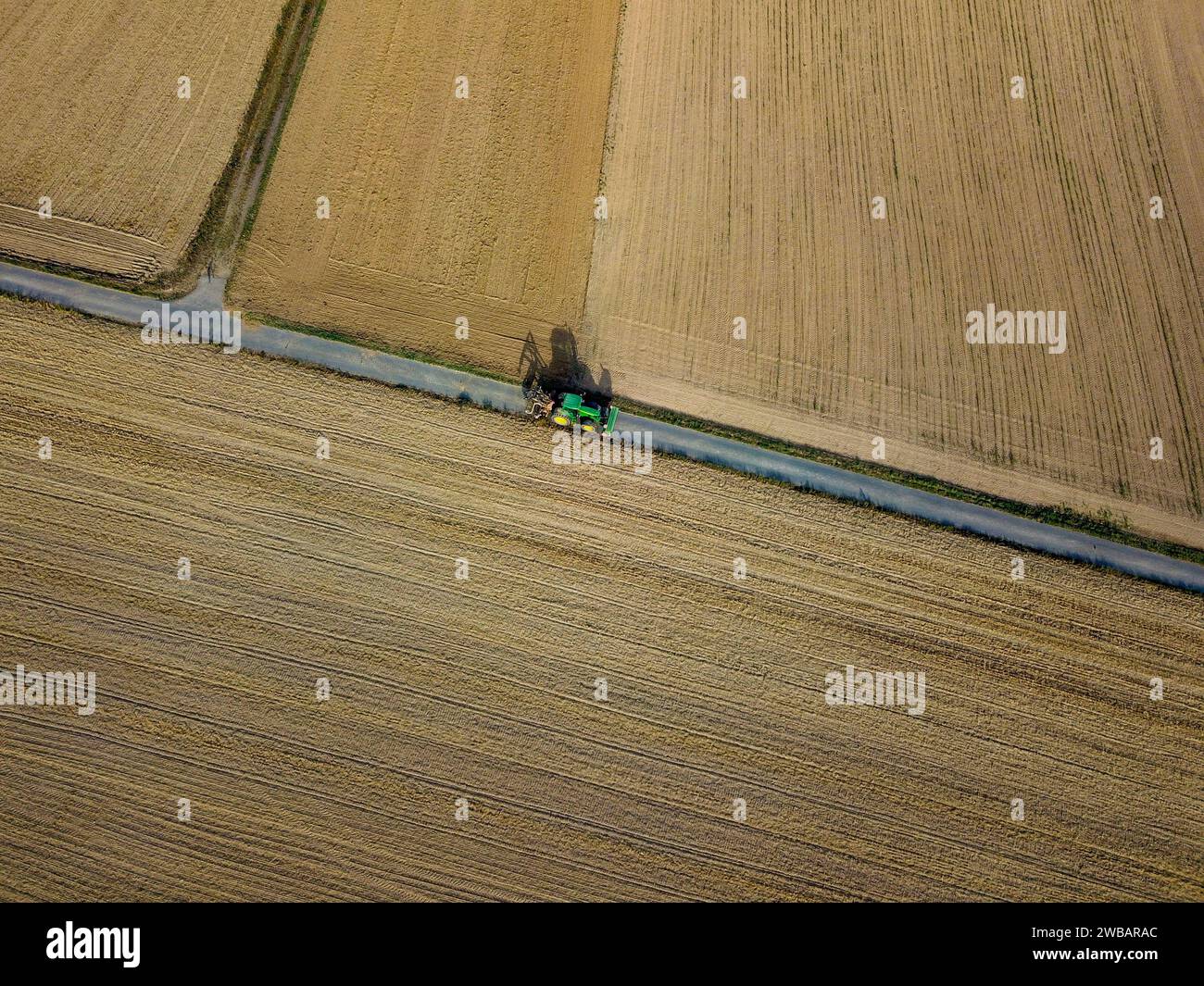 A farmer driving through his harvested fields in summer, photographed ...