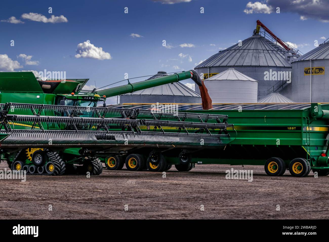 A large tractor trailer is transporting a grain mill on its back, with ...