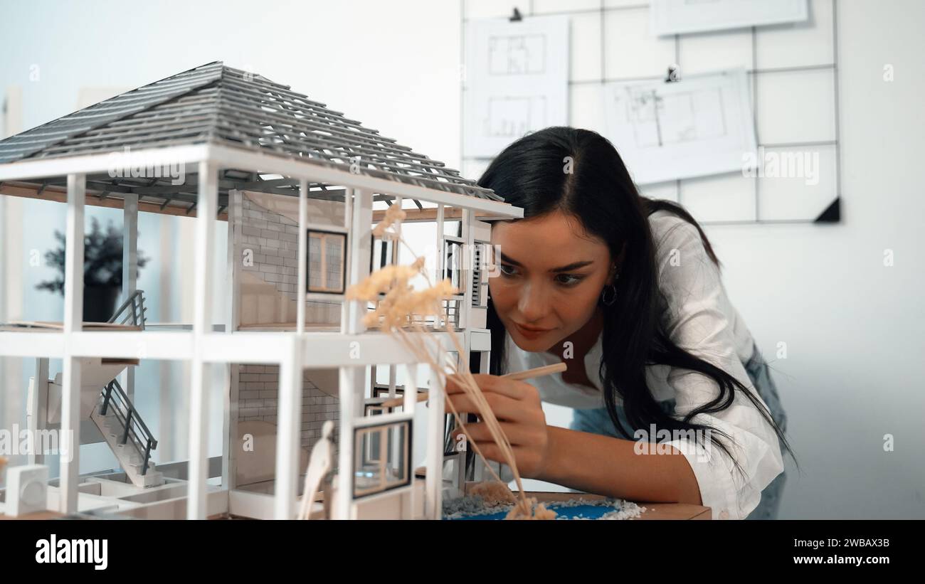 Young beautiful caucasian architect engineer turns house model around ...