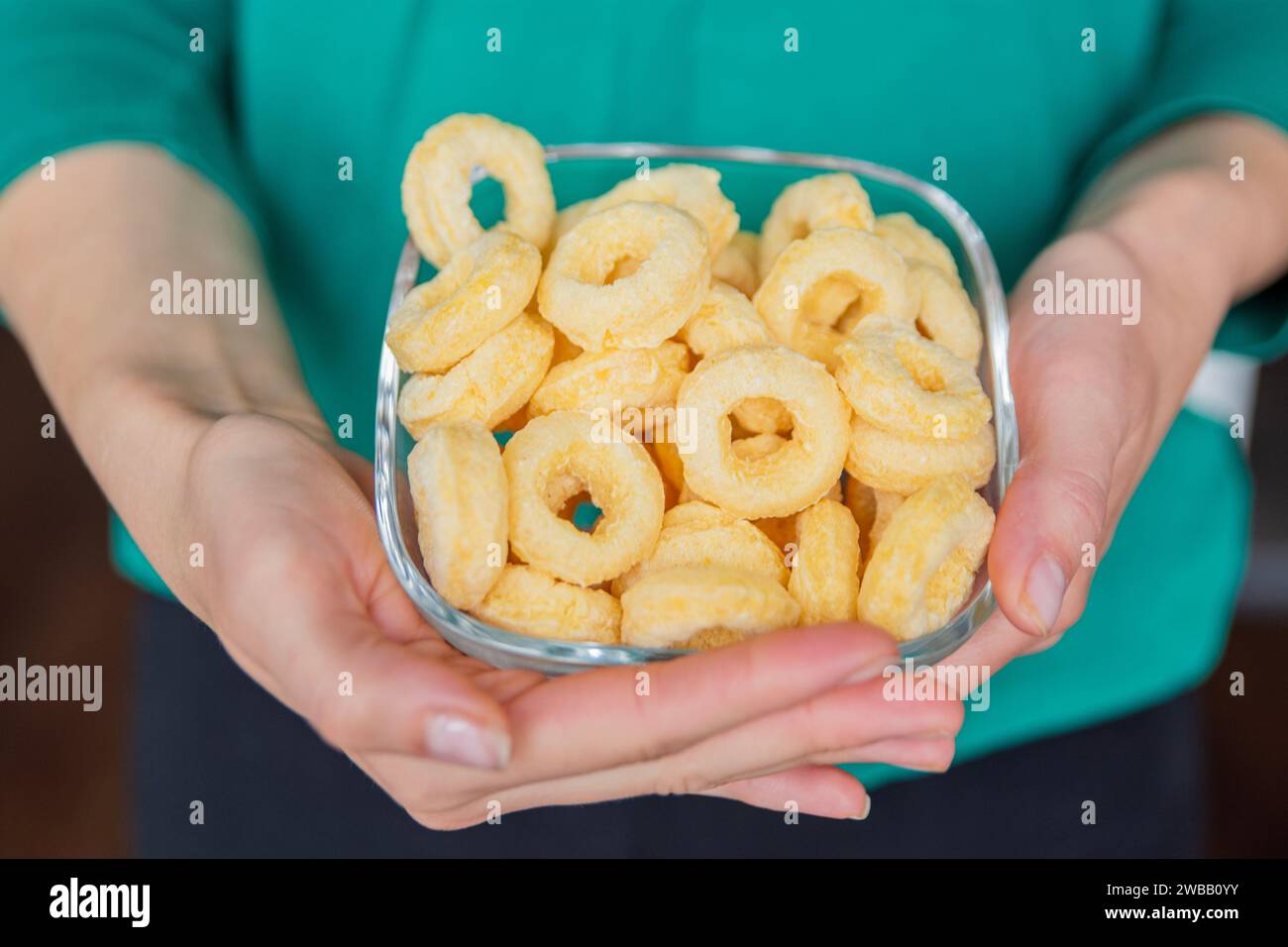 Hand holding corn rings close-up. Round yellow chips are a quick snack ...