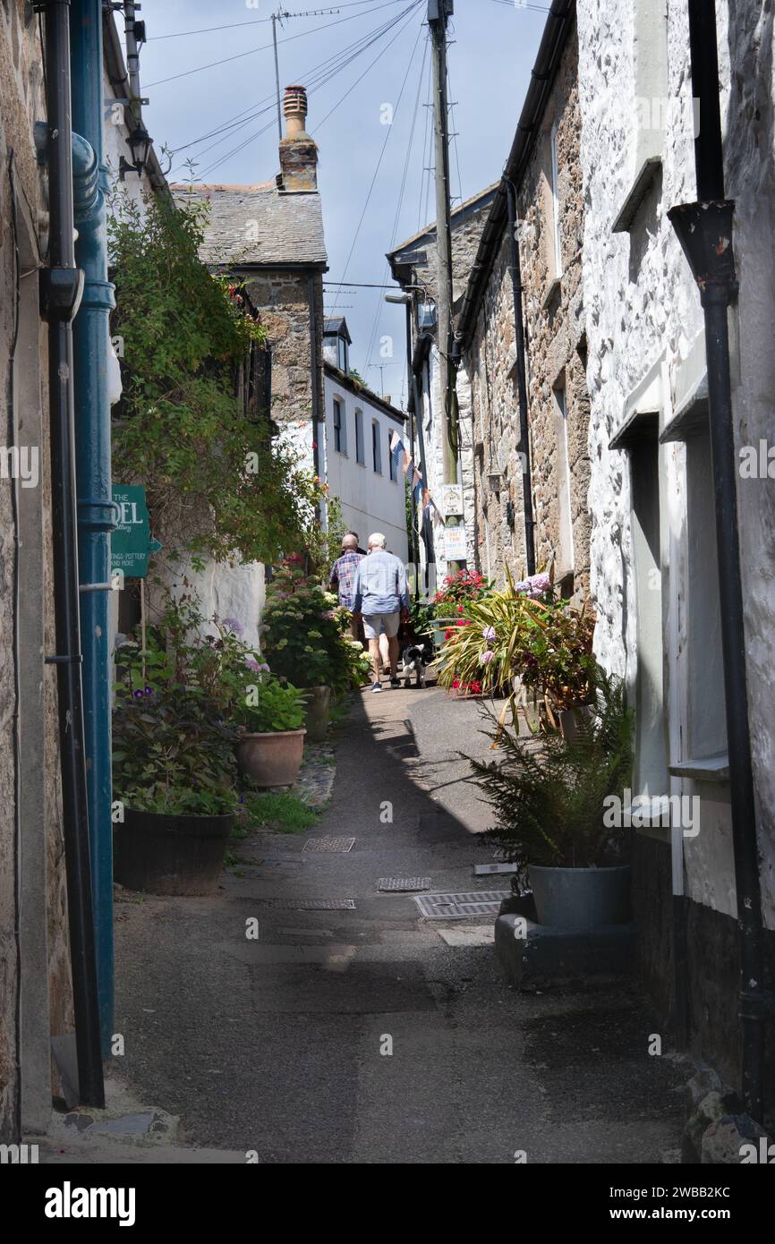 Back of two men walking down a pretty narrow street in Mousehole a ...
