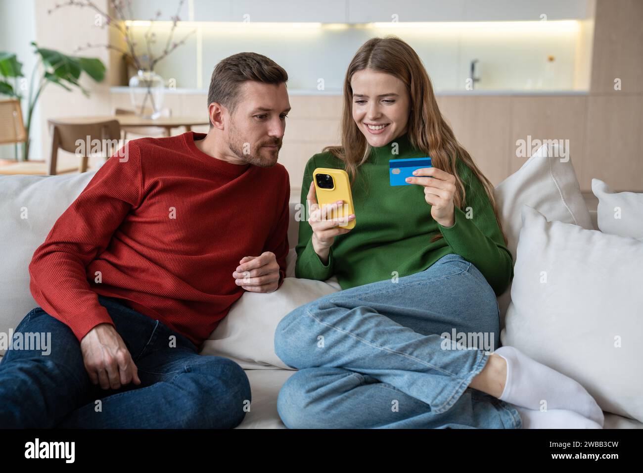 Online family shopping. Delighted young woman with credit card looks at ...