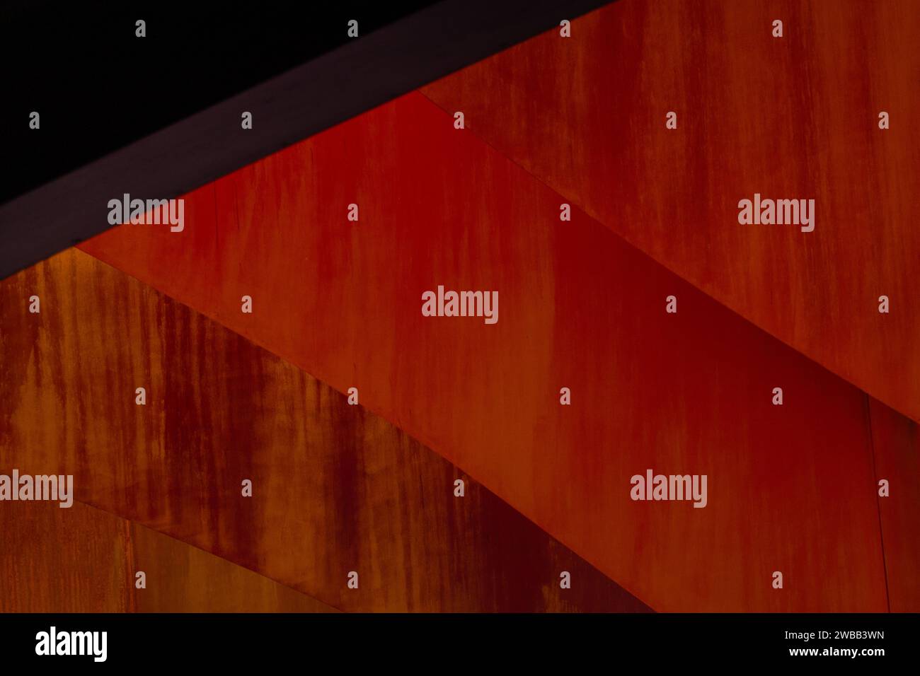 Vivid abstract architectural detail with intersecting red and orange planes creating a dynamic ...