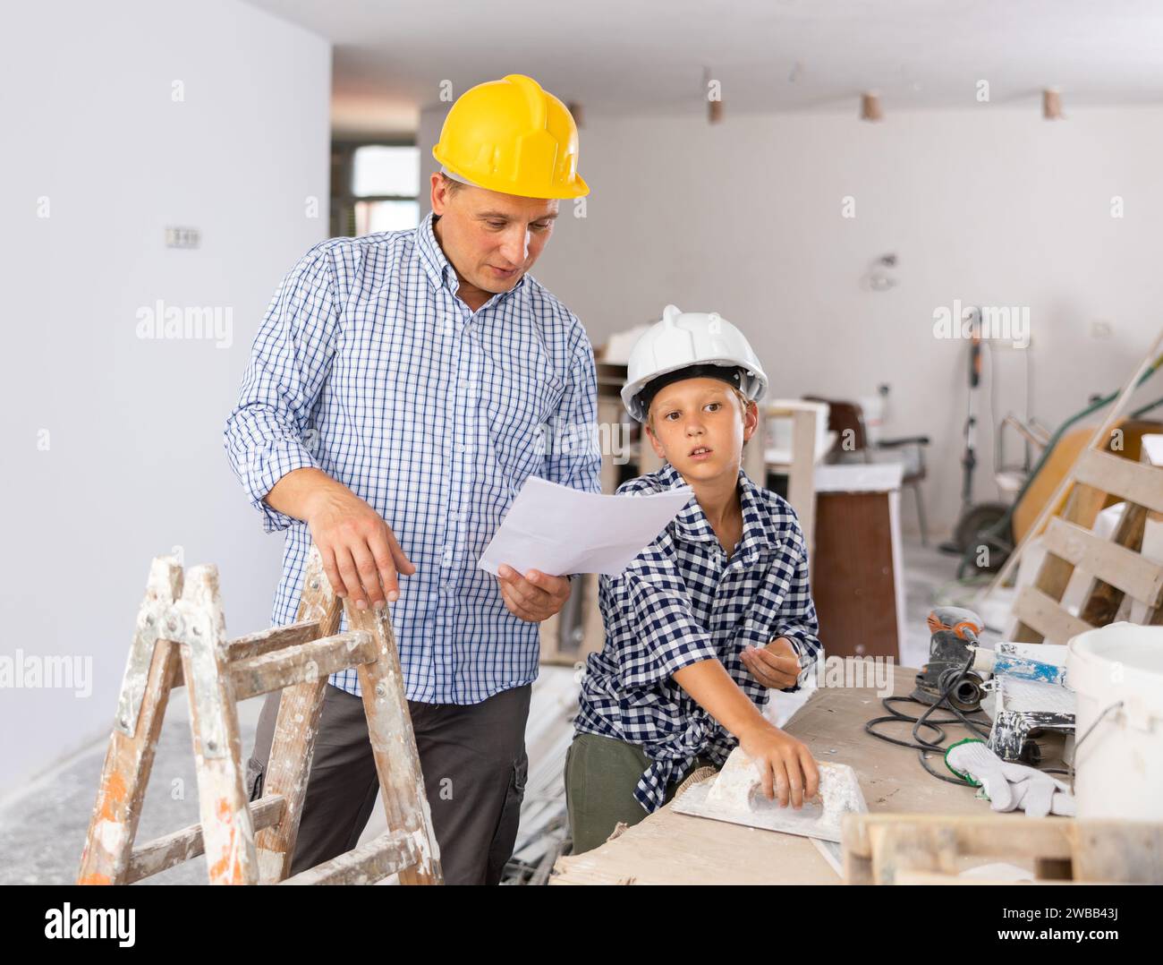 Father and his young son discussing work plan in construction site ...