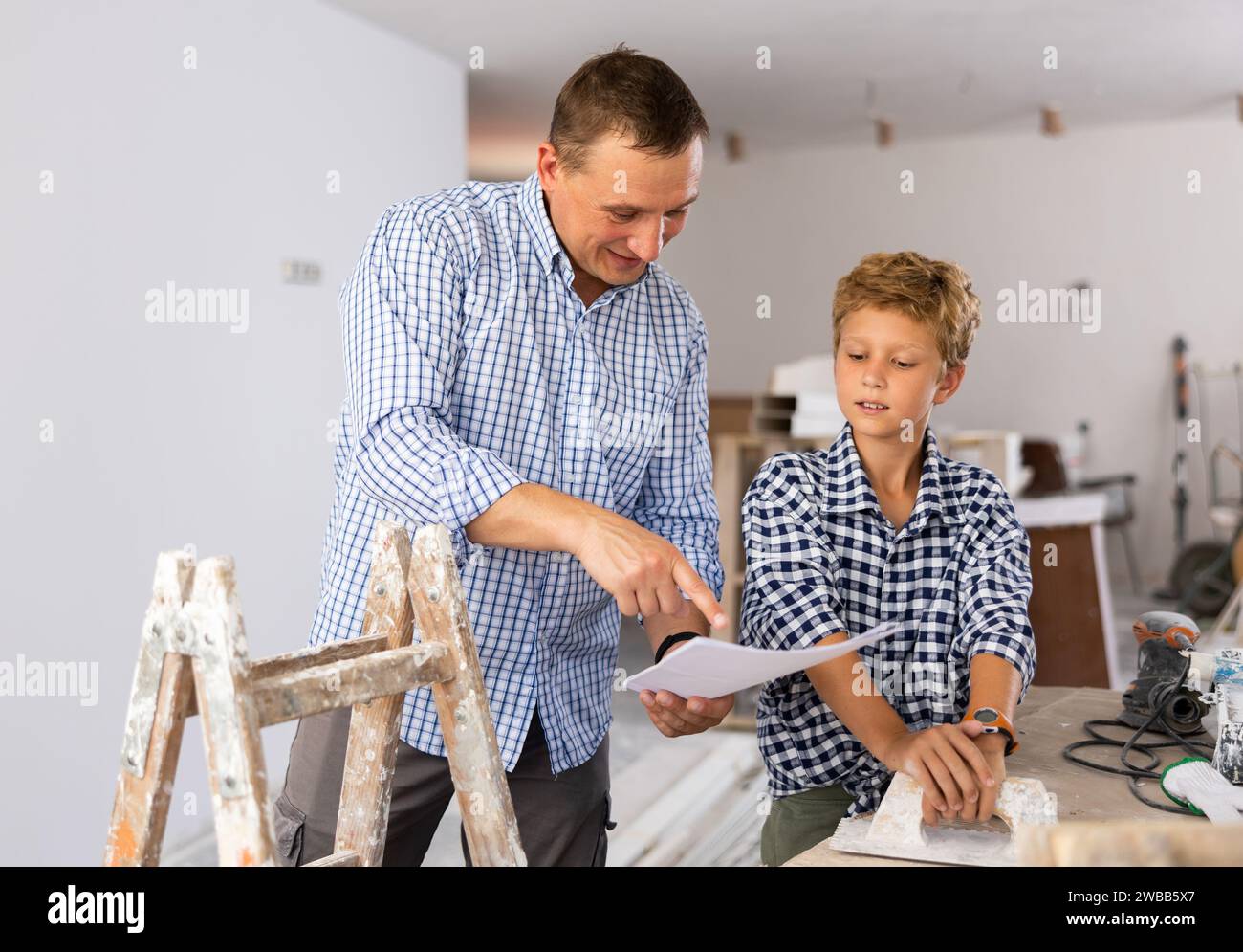 Father and his young son discussing work plan in construction site ...