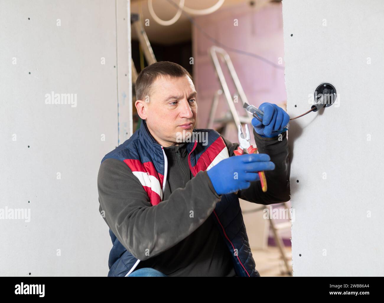 Professional builder engaged in electrical installation work at indoors ...