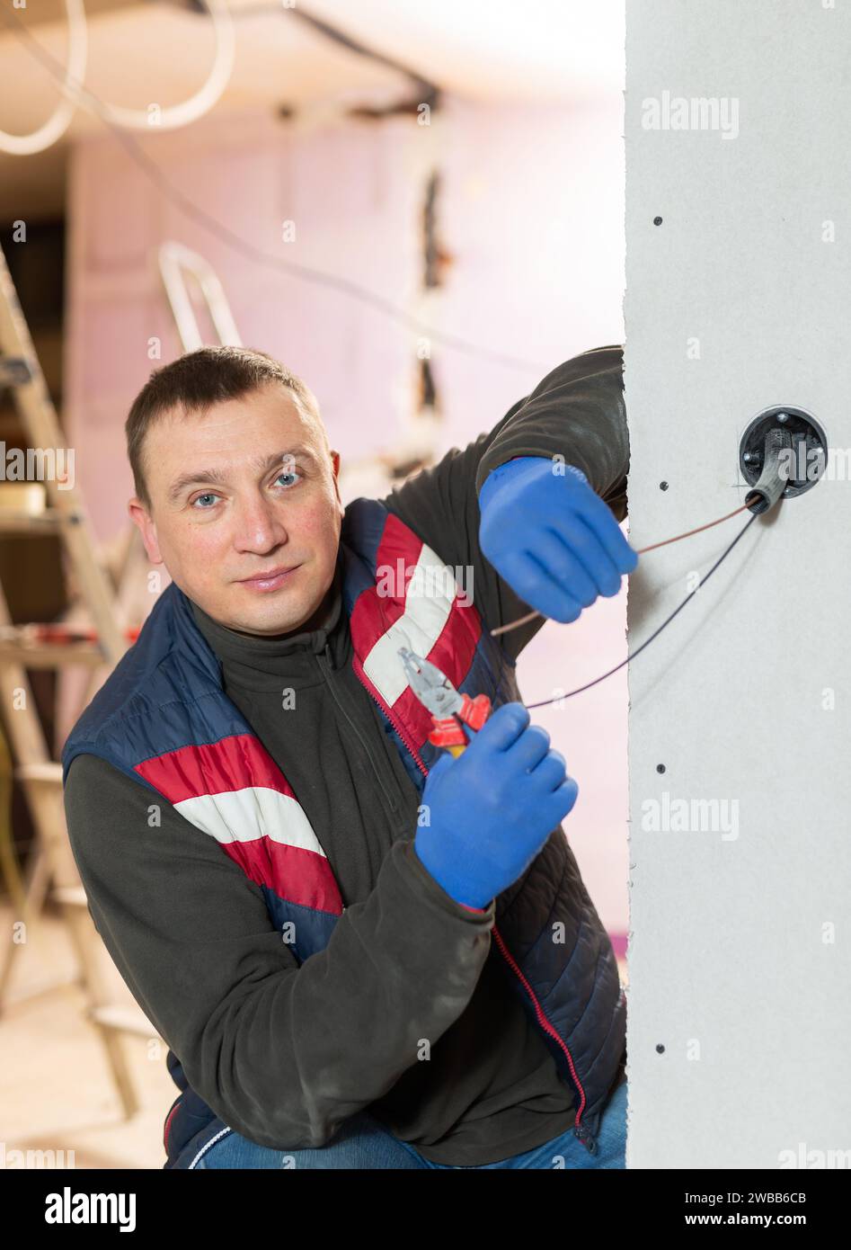 Professional builder engaged in electrical installation work at indoors ...