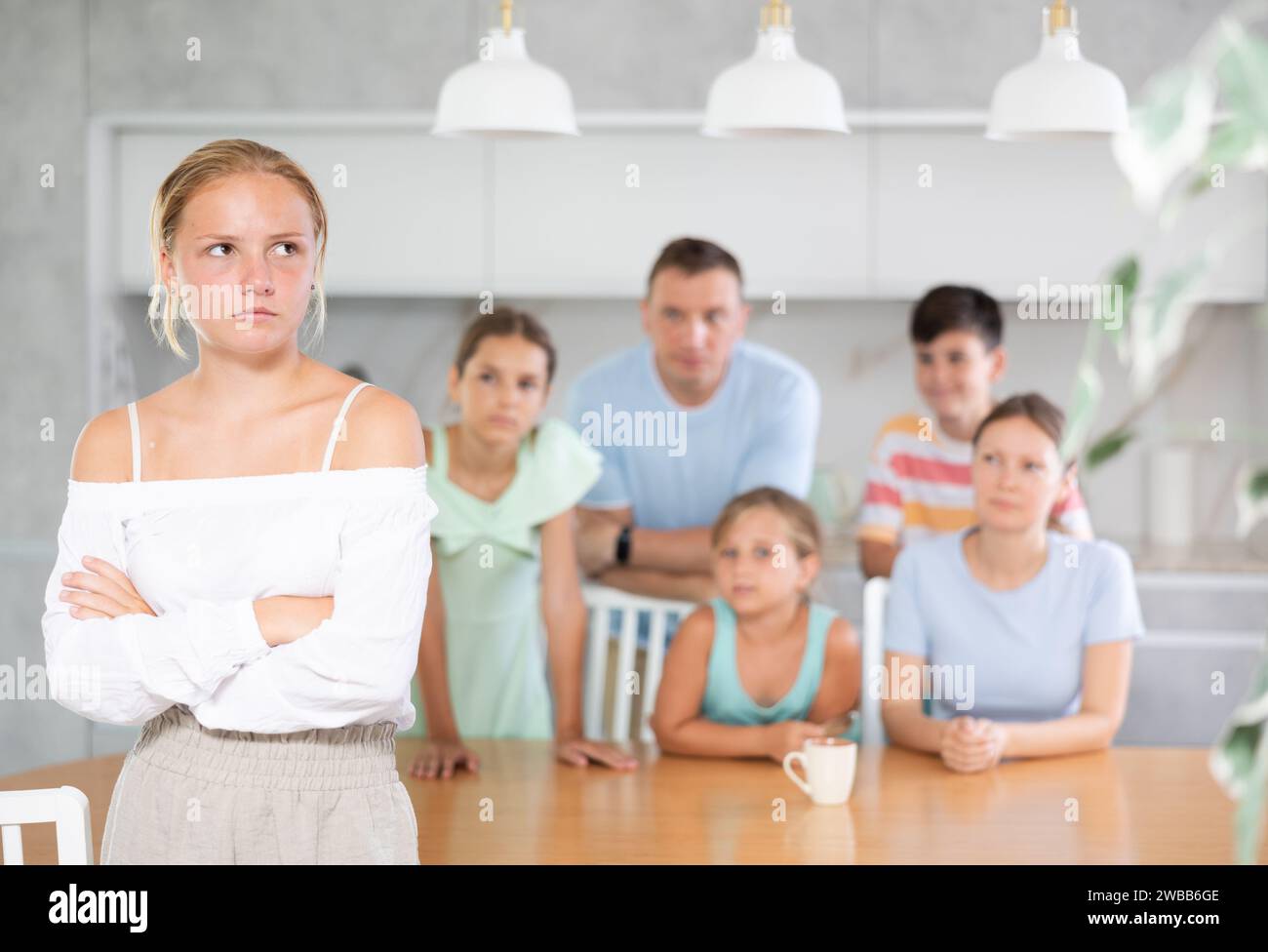 Angry female child turned away from parents and sisters and ignores ...