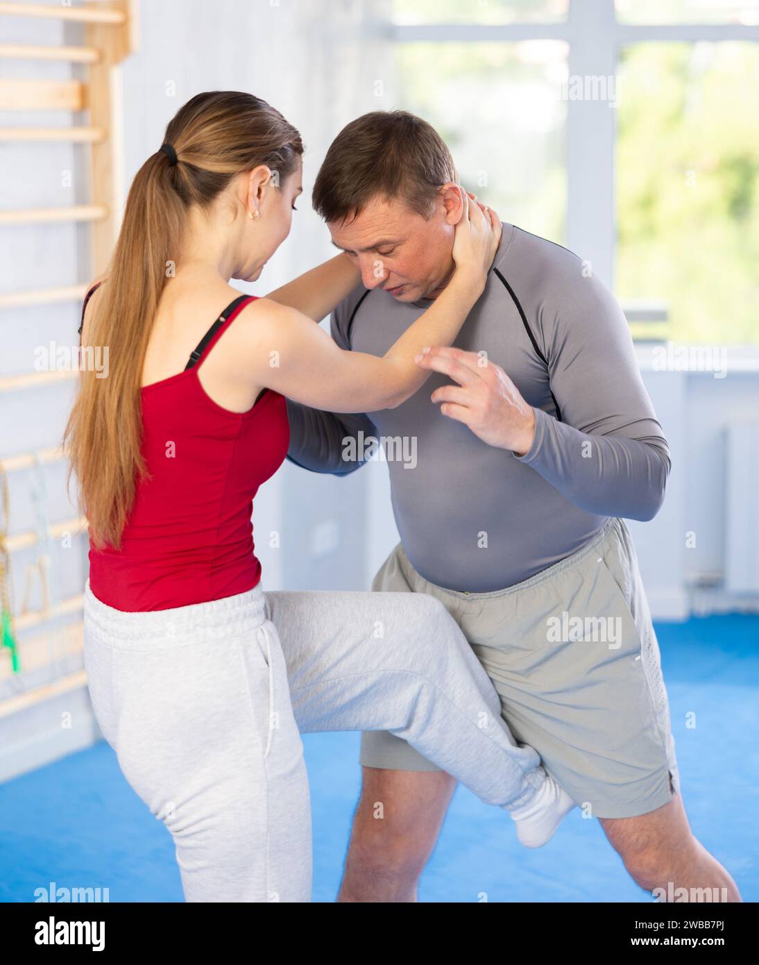 Young girl practicing feet kick method of self-defense in pair with ...