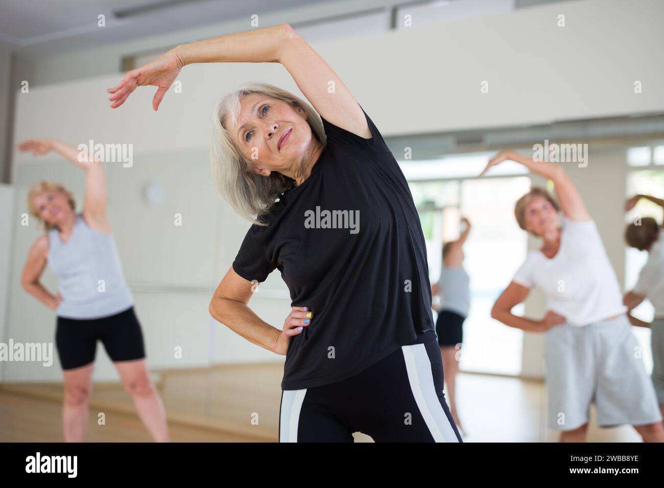Mature woman making stretching exercises in fitness studio Stock Photo ...