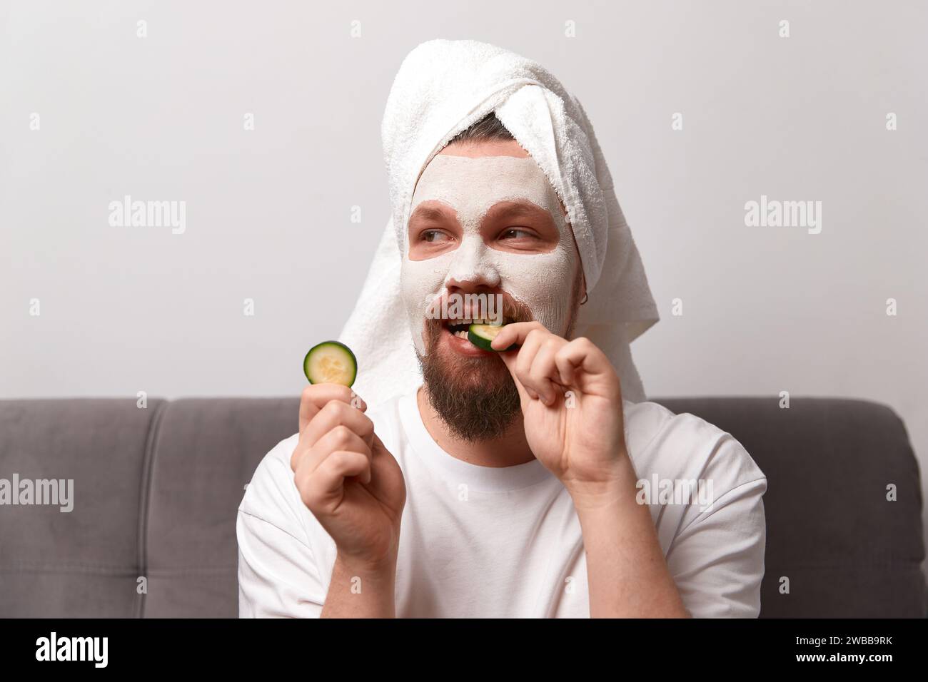 Portrait of funny happy man in white tshirt applying cucumber slices ...