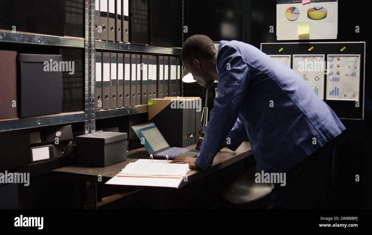 In neatly organised office, african american detective examines ...