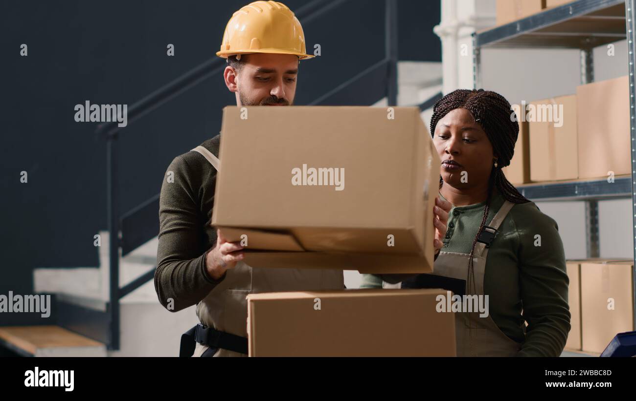 Manager wearing hardhat in warehouse teaching african american intern ...