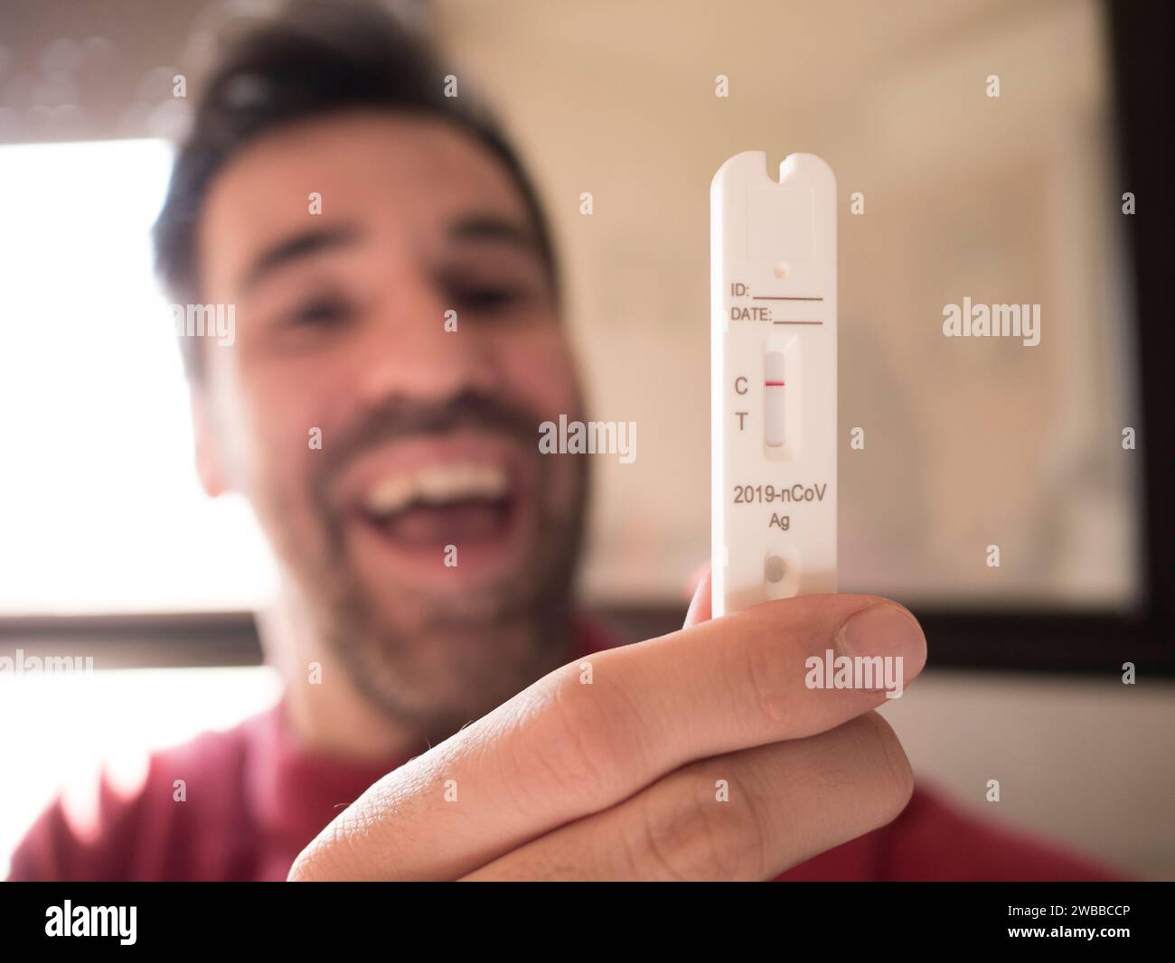 Man holds negative COVID test, out of focus, joyful with mouth open, at ...