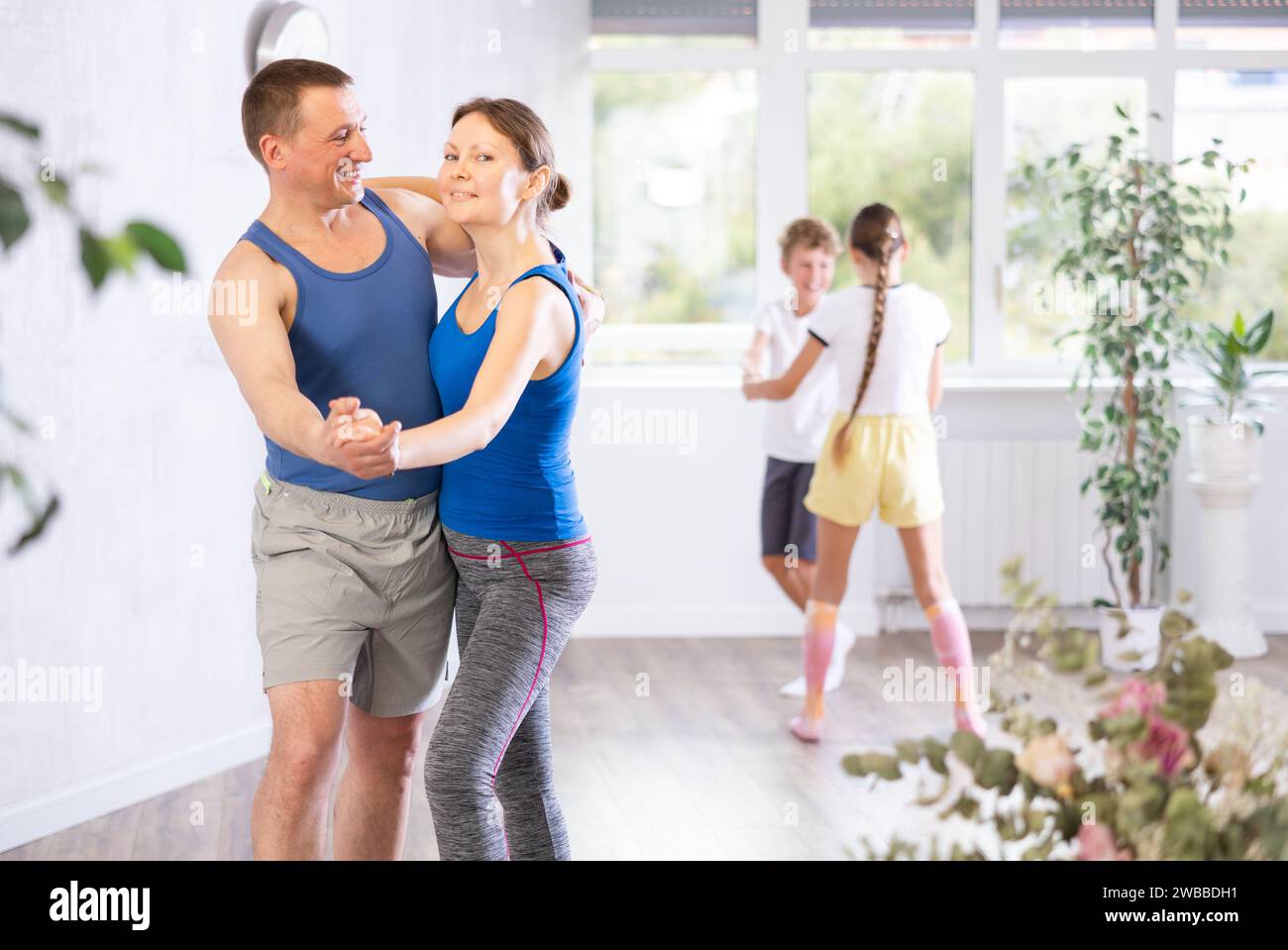Mother and father learning dynamic boogie-woogie in pair in dance ...