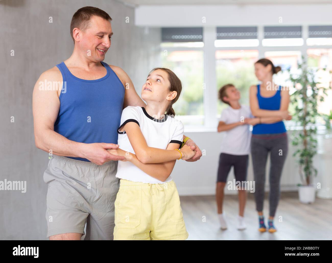 Happy father and daughter practicing dance in pairs together with other ...
