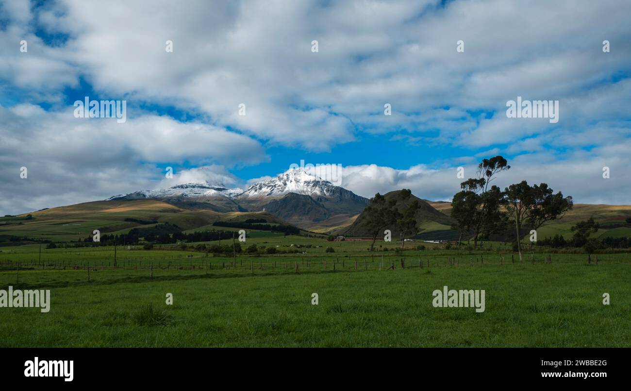 Panoramic view of ice-covered Los Ilinizas volcano over green fields ...