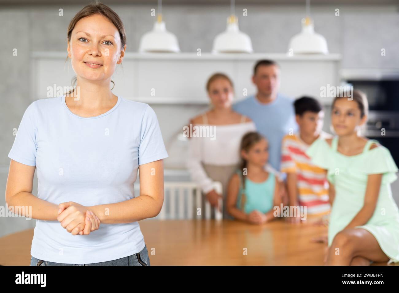 Smiling mum poses in cozy kitchen, large family with four children and ...