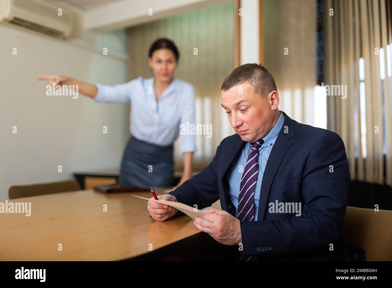 Shocked office employe reading papers with dissatisfied female manager ...