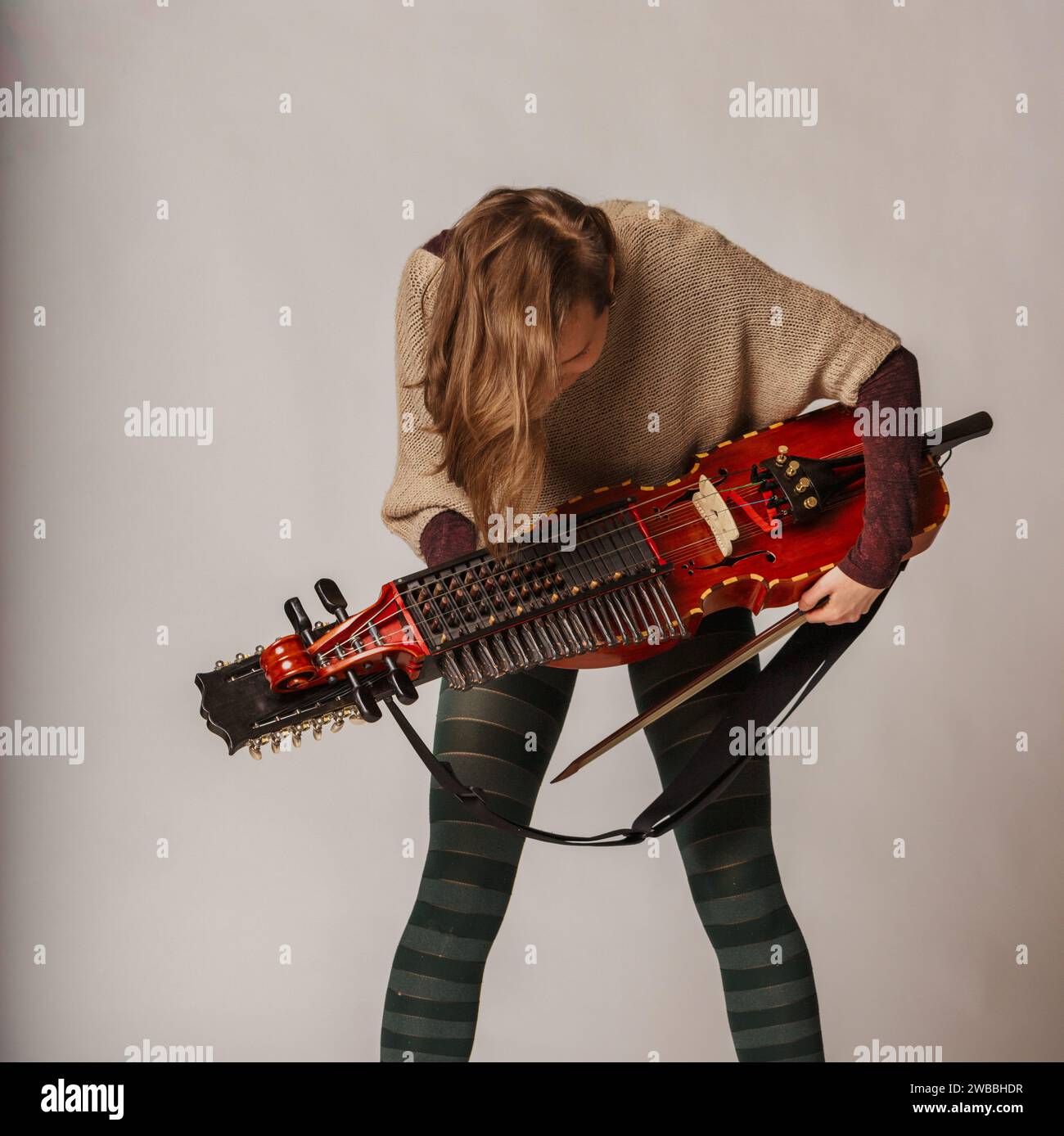 musician closely inspects her nyckelharpa, a rare traditional Swedish ...
