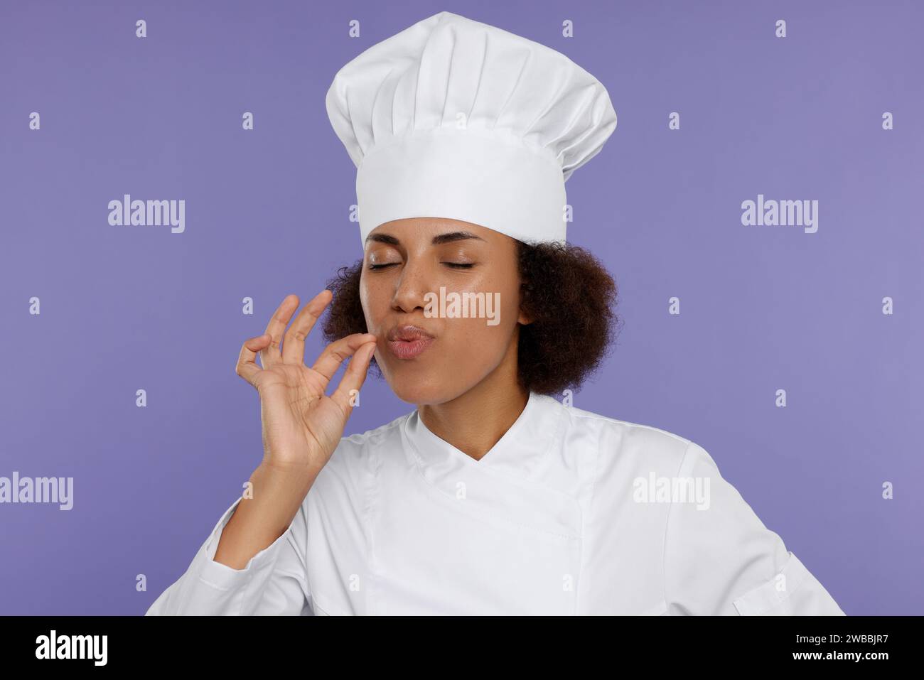 Happy female chef in uniform showing perfect sign on purple background ...