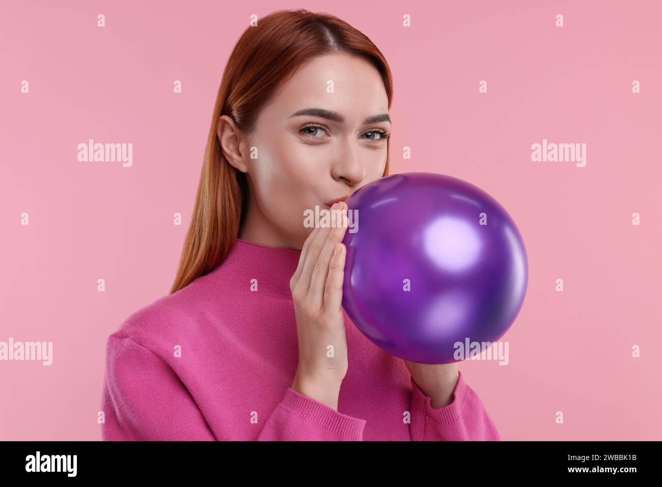 Woman inflating purple balloon on pink background Stock Photo - Alamy