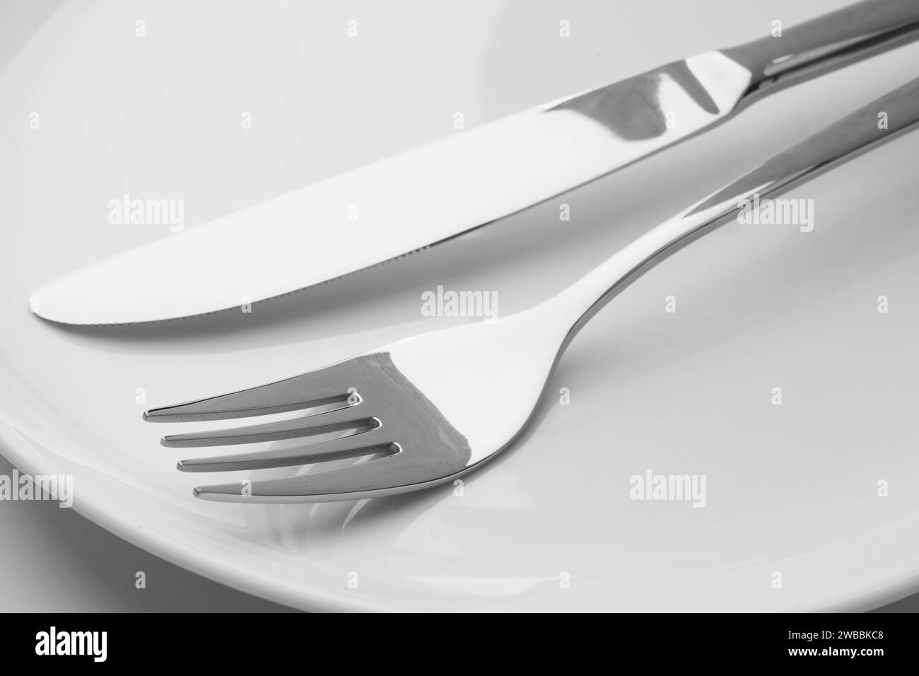 Clean plates, fork and knife, closeup view Stock Photo - Alamy