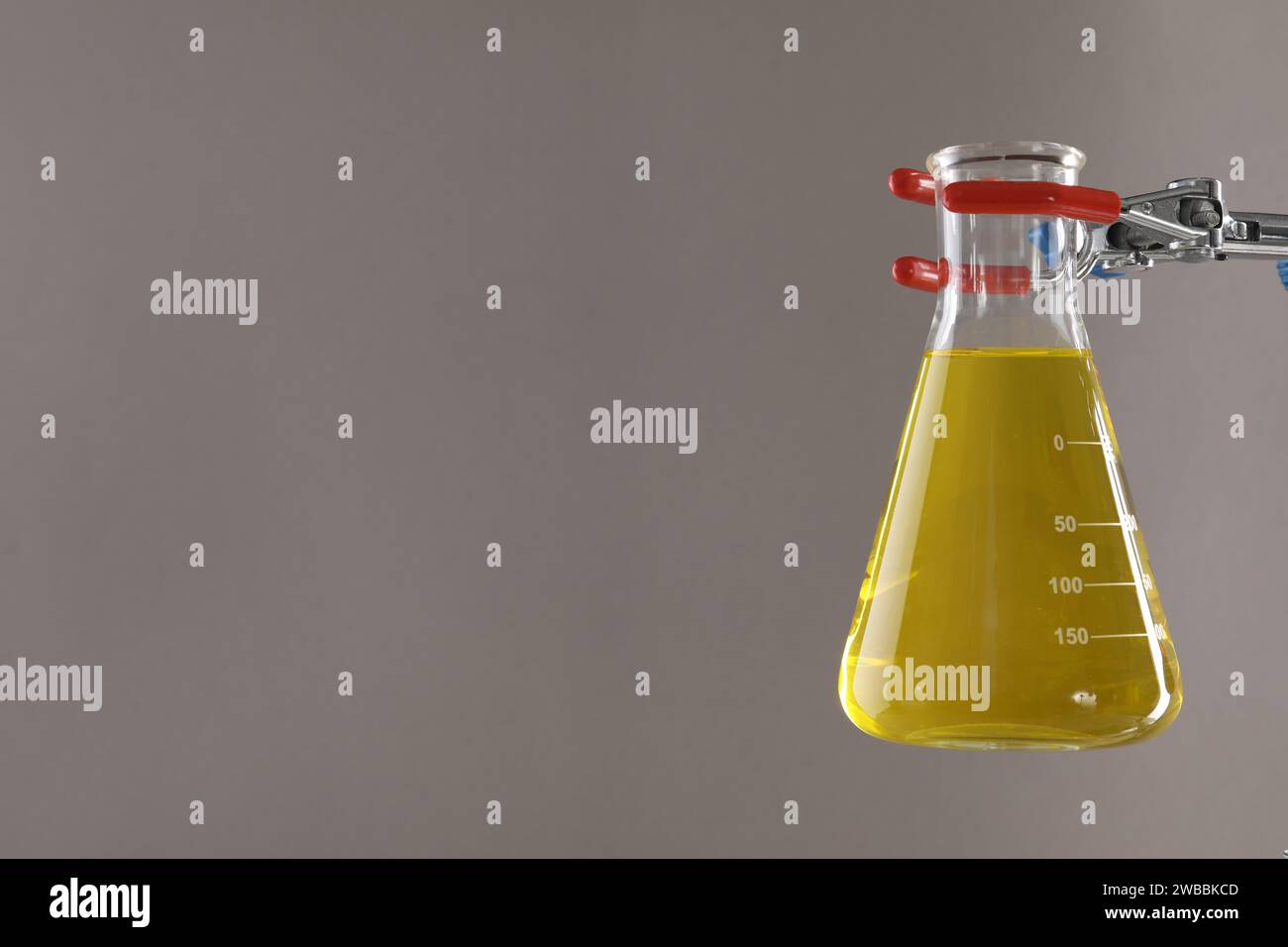 Retort stand and laboratory flask with liquid on light grey background ...