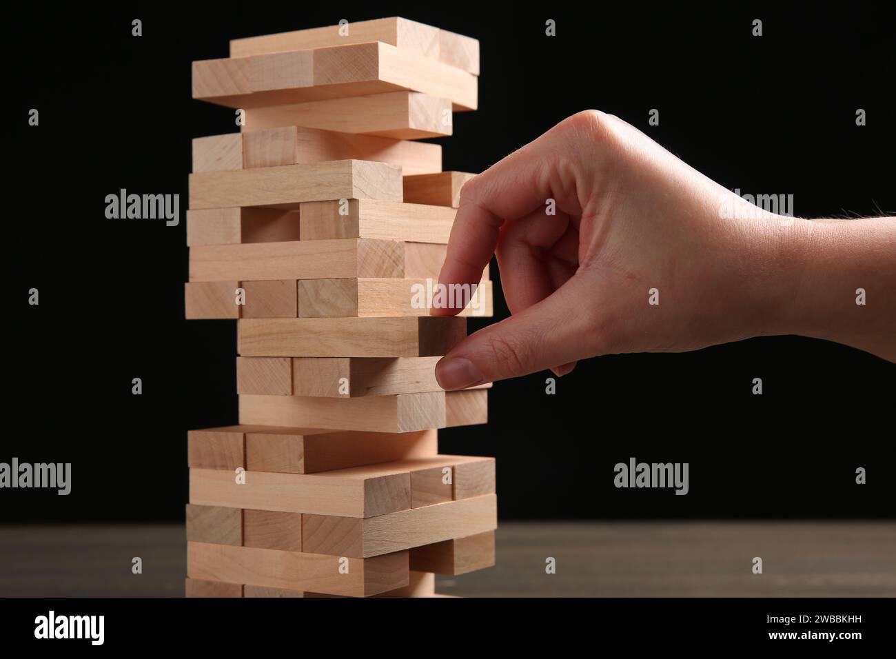Woman playing Jenga at table against black background, closeup Stock ...