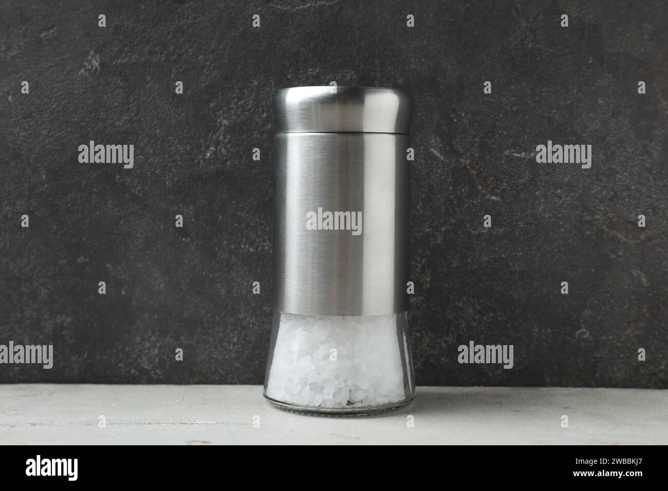 Salt shaker on light table against grey background, closeup Stock Photo ...