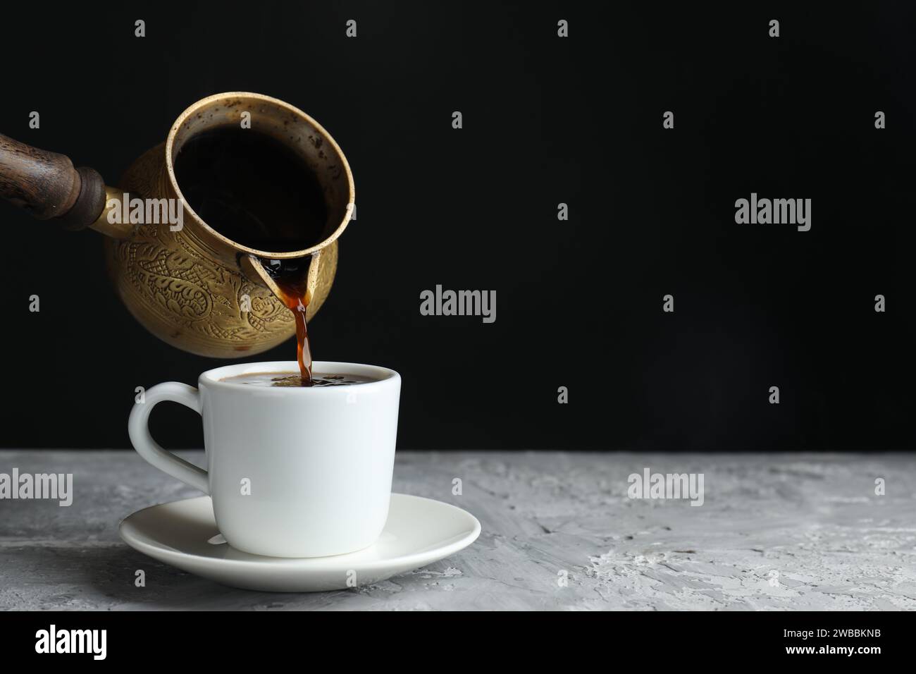 Turkish coffee. Pouring brewed beverage from cezve into cup at grey ...