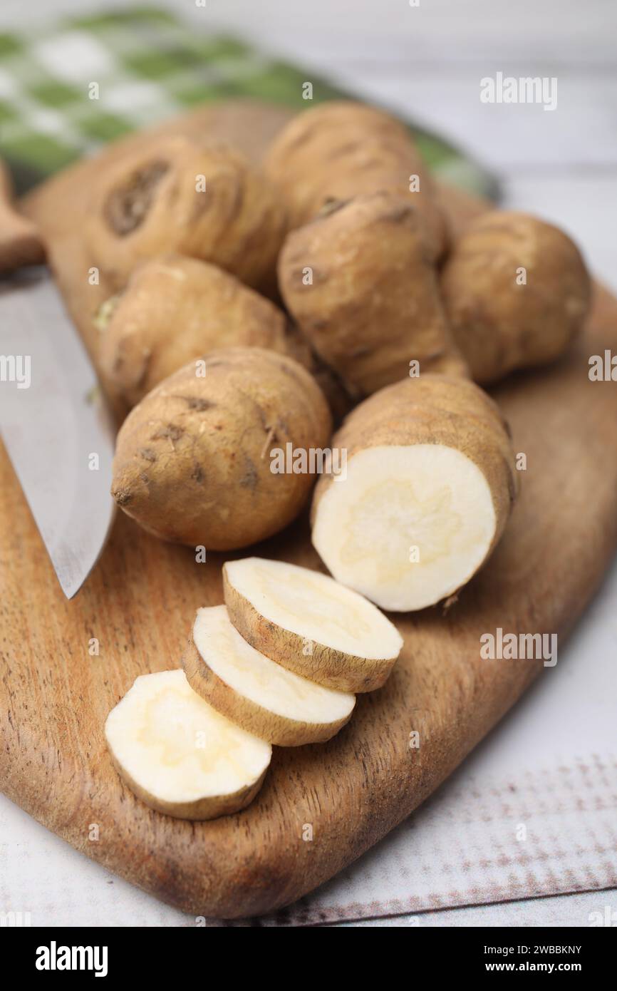 Whole and cut turnip rooted chervil tubers on light wooden table ...