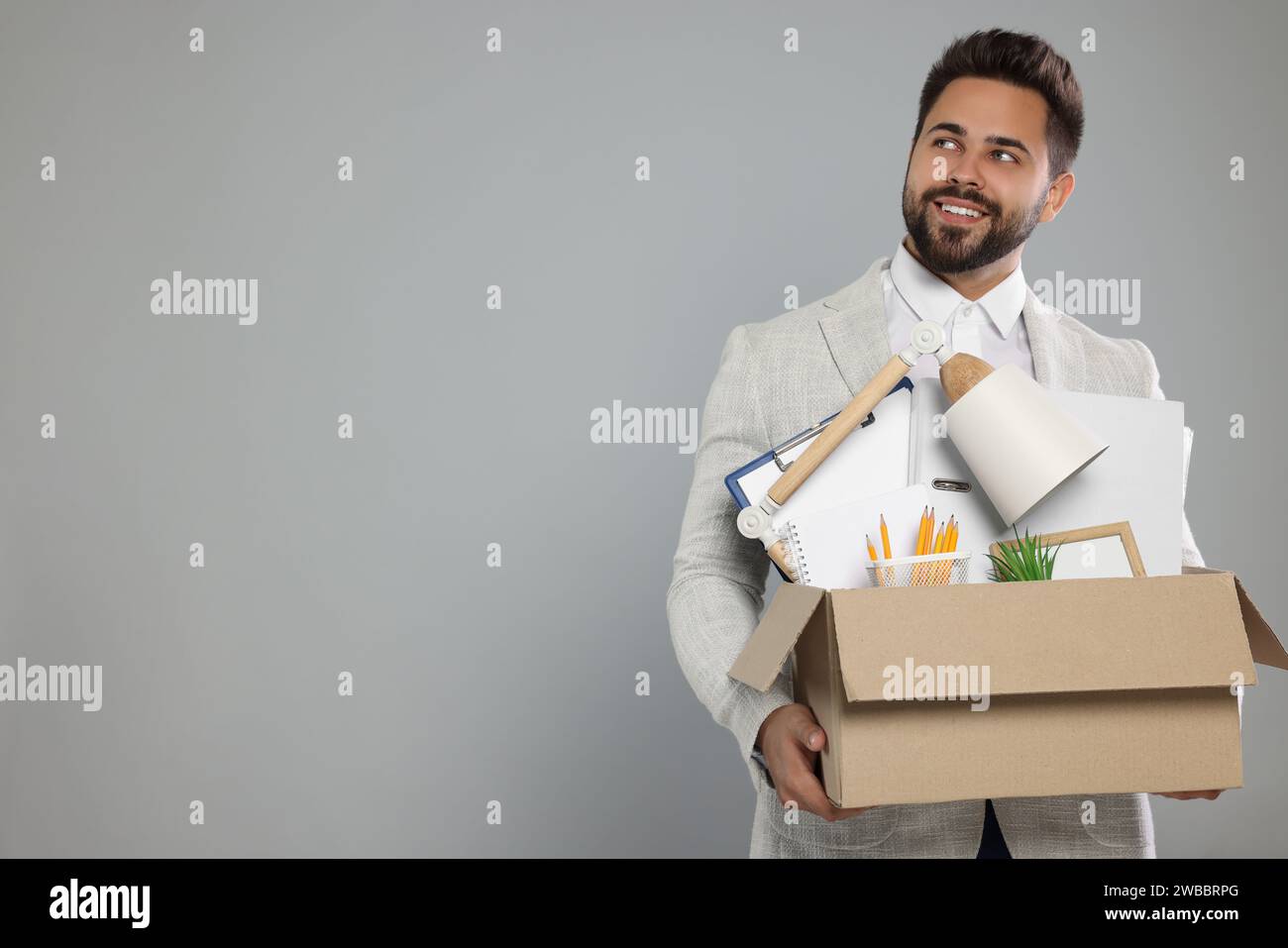 Happy unemployed man with box of personal office belongings on light ...