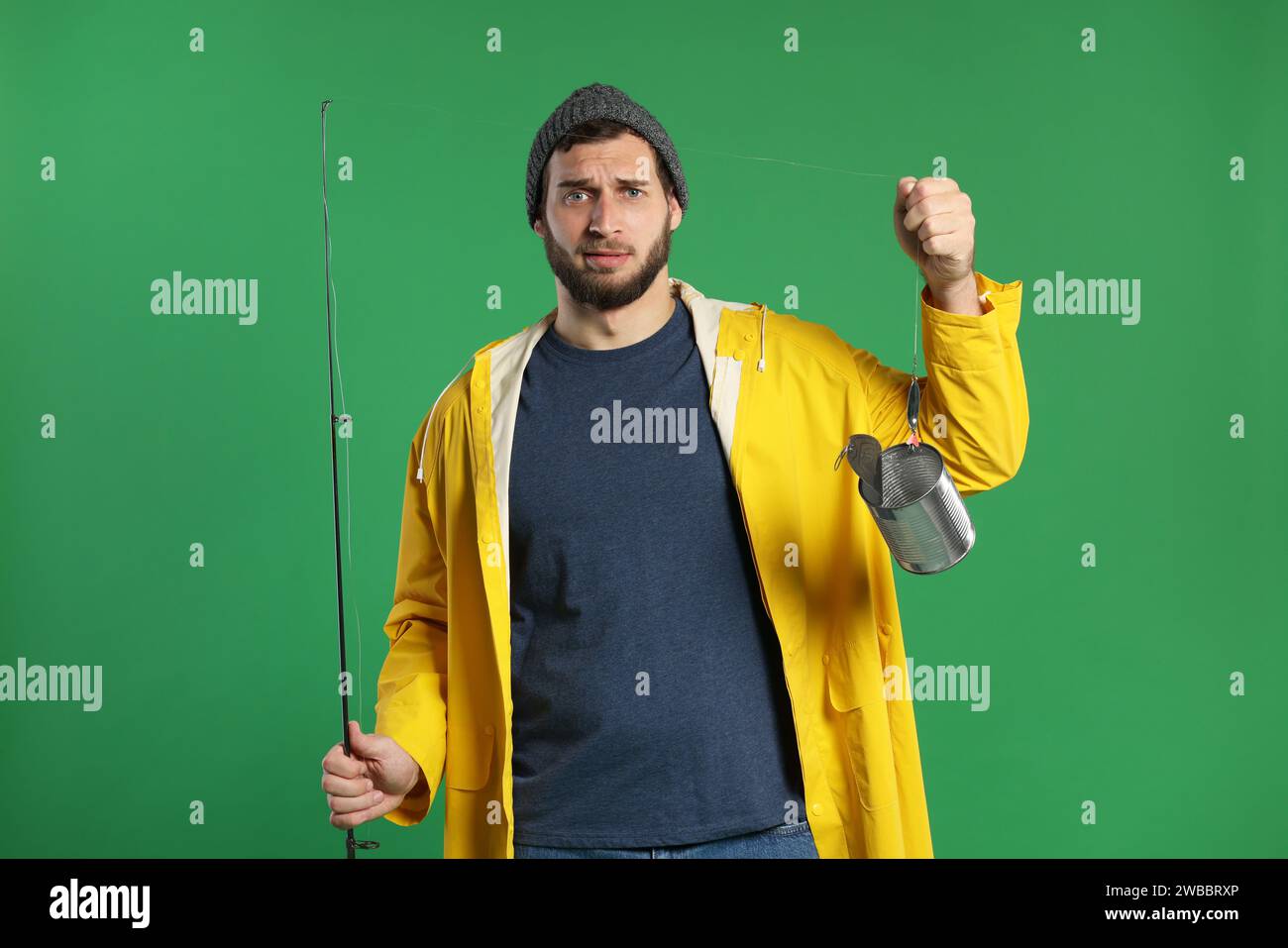 Confused fisherman with fishing rod and tin can on green background ...