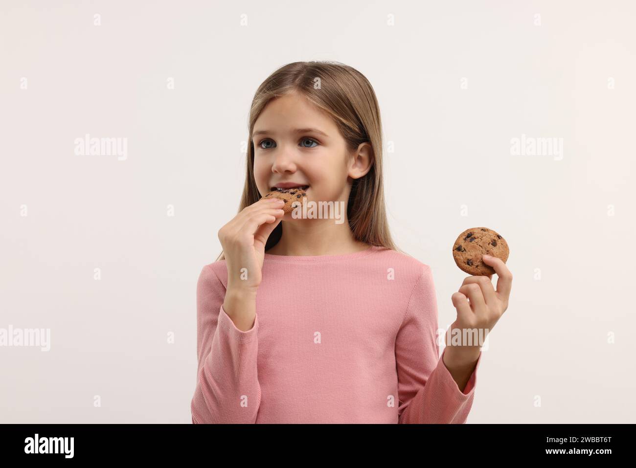 Cute girl eating chocolate chip cookies on white background Stock Photo ...