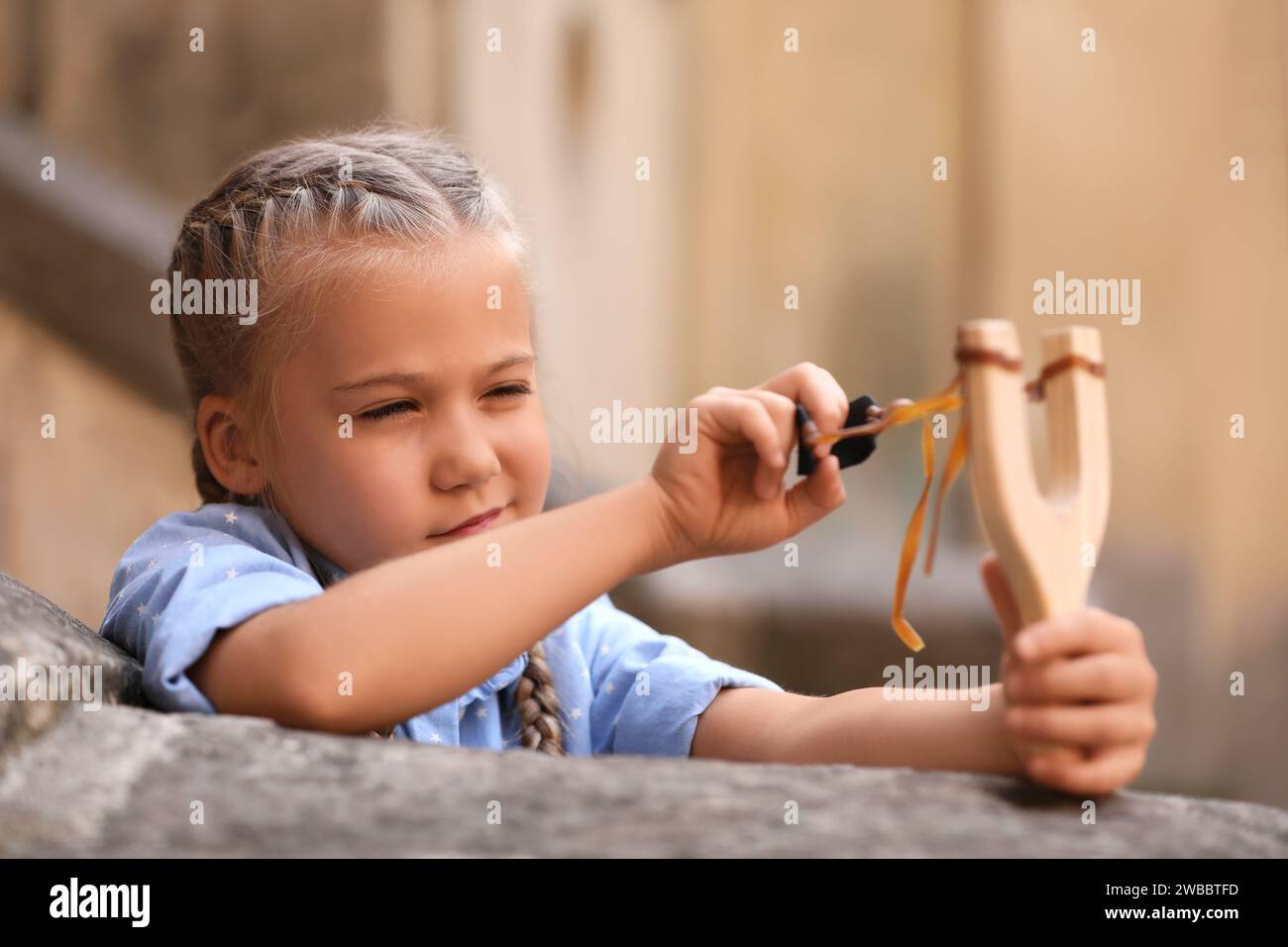 Cute little girl playing with slingshot outdoors Stock Photo - Alamy
