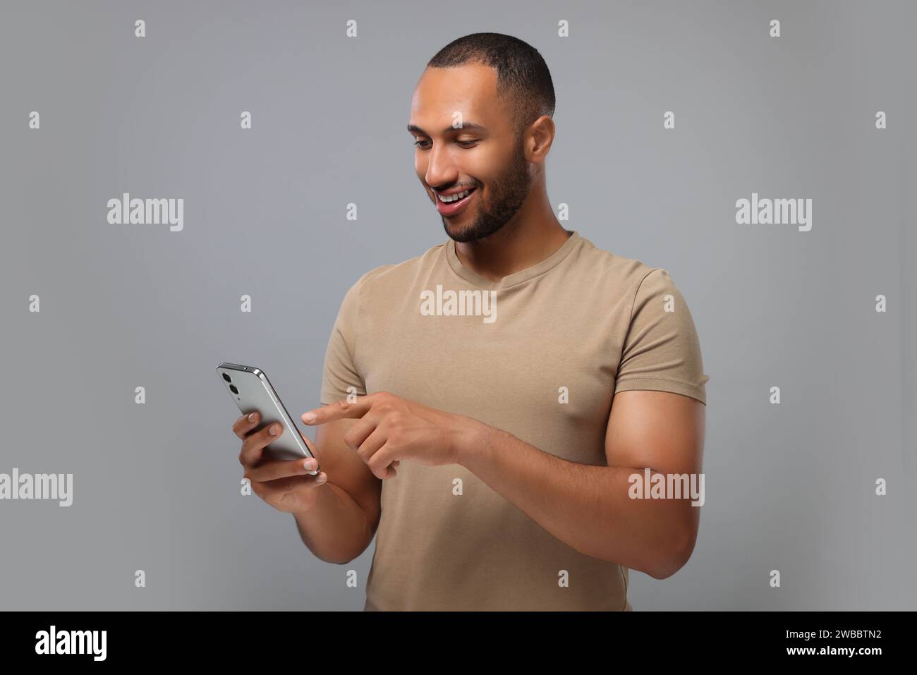 Happy man sending message via smartphone on grey background Stock Photo ...
