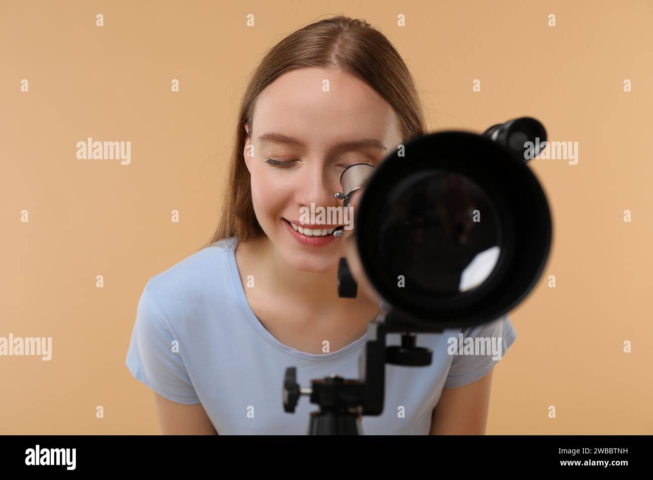 Young astronomer looking through telescope on beige background Stock ...
