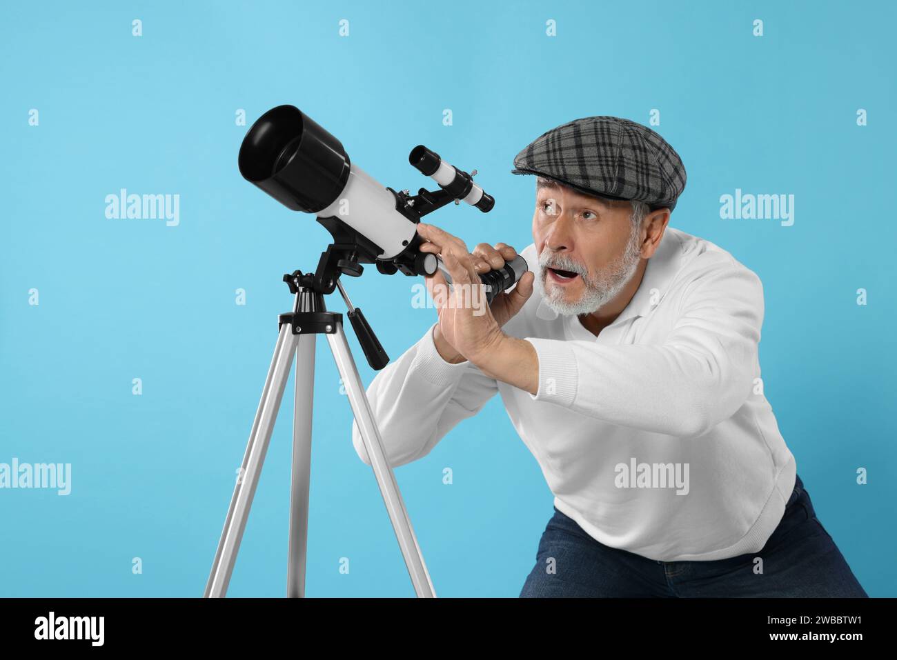 Senior astronomer with telescope on light blue background Stock Photo ...