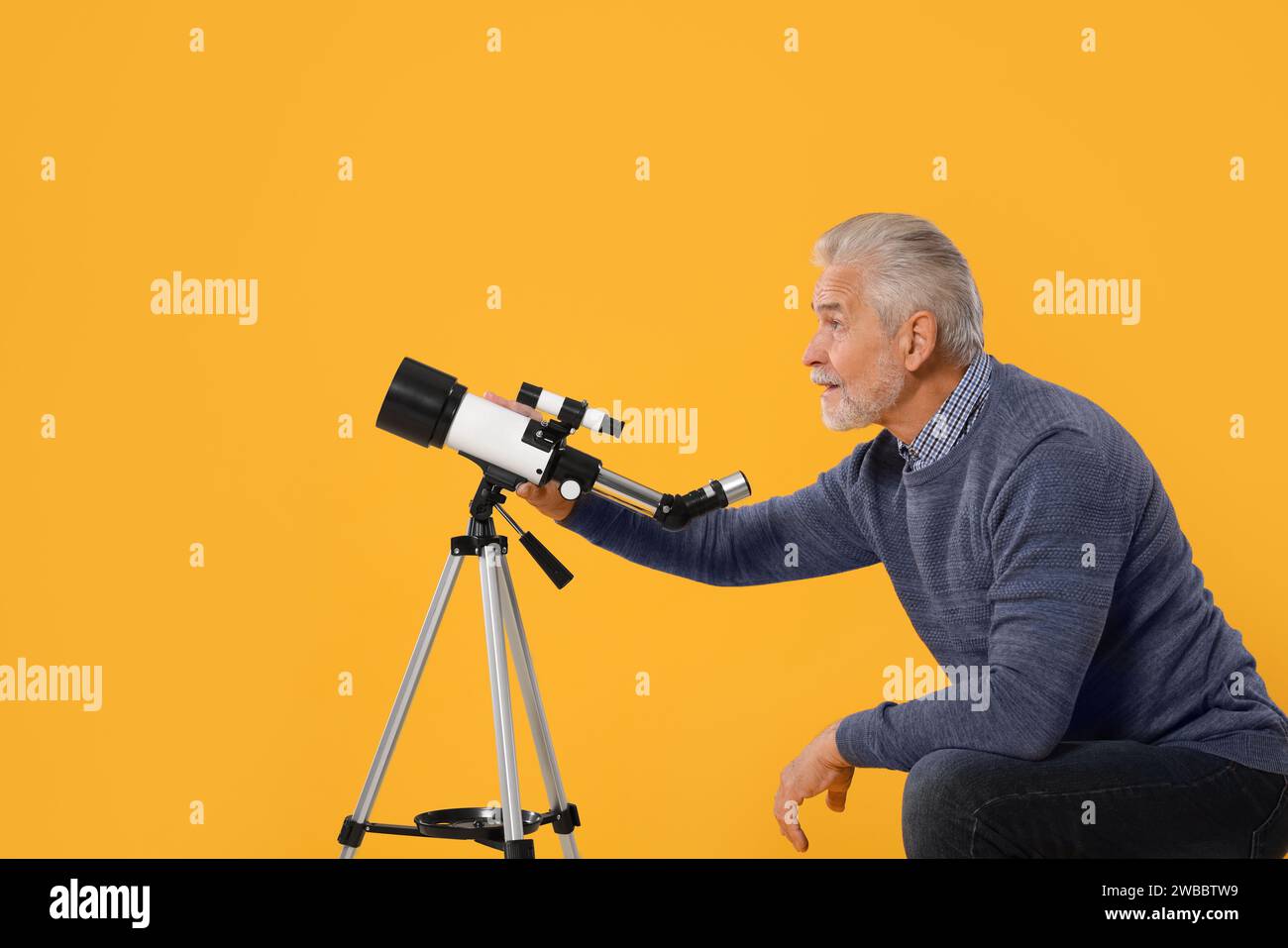 Senior astronomer with telescope on yellow background Stock Photo - Alamy